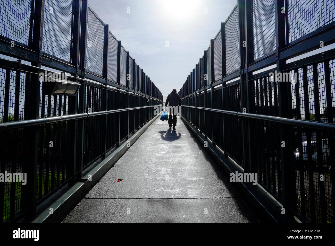 silhouette of a man walking on a narrow railway overpass in Bedford ...