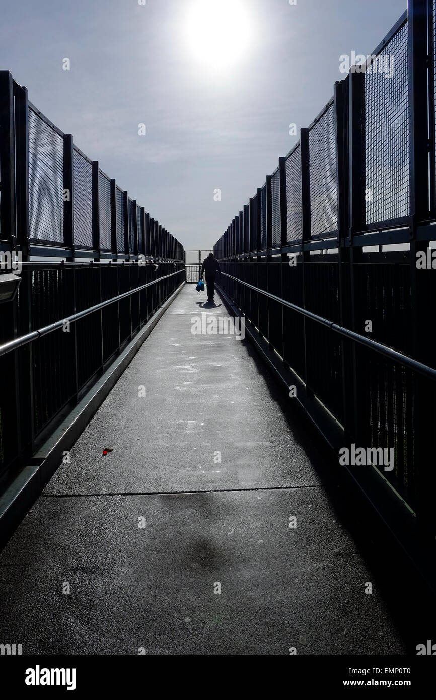 silhouette of a man walking on a narrow railway overpass in Bedford ...
