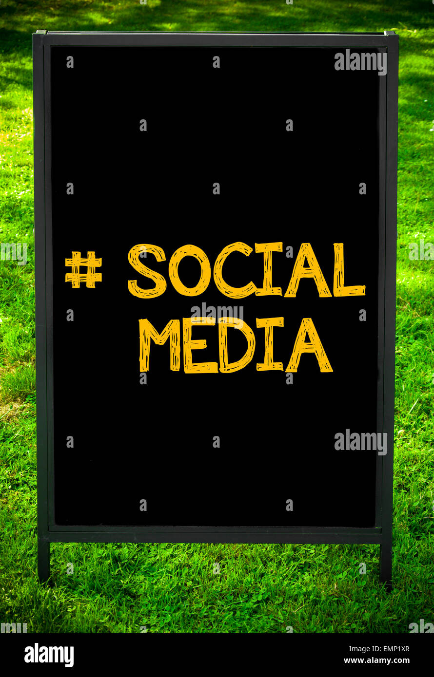 Hashtag Social Media message on sidewalk blackboard sign against green ...