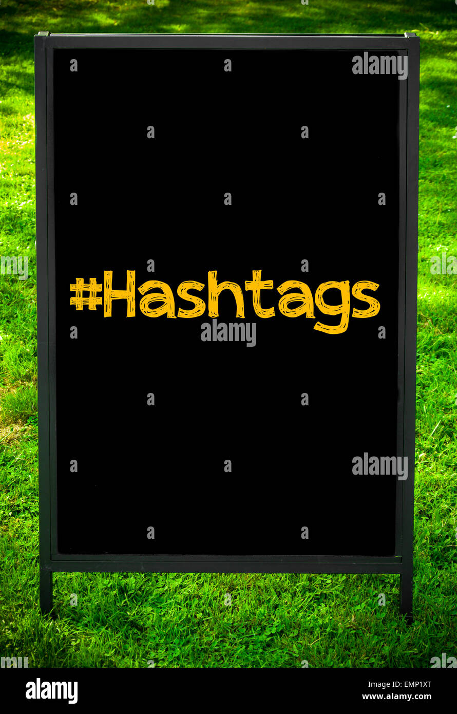 HASHTAGS message on sidewalk blackboard sign against green grass ...