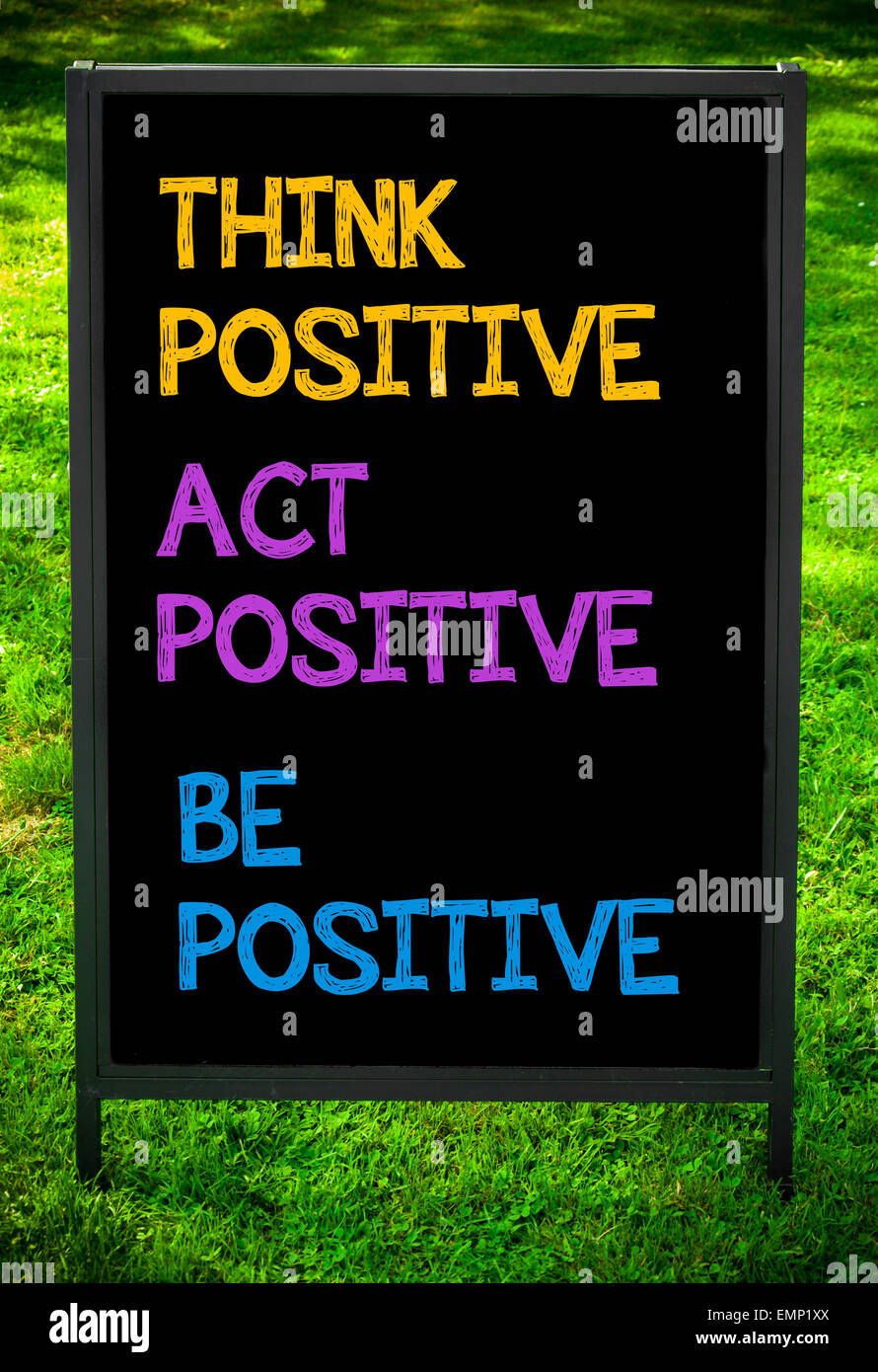 THINK ACT BE POSITIVE message on sidewalk blackboard sign against green ...