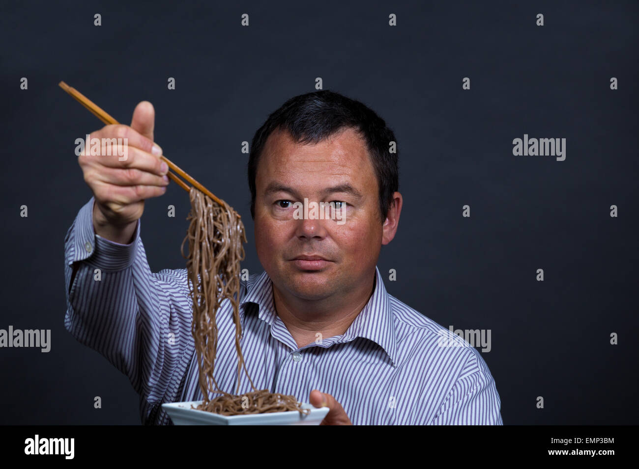Guy getting pretty fed up with his attempts on eating with chopsticks ...