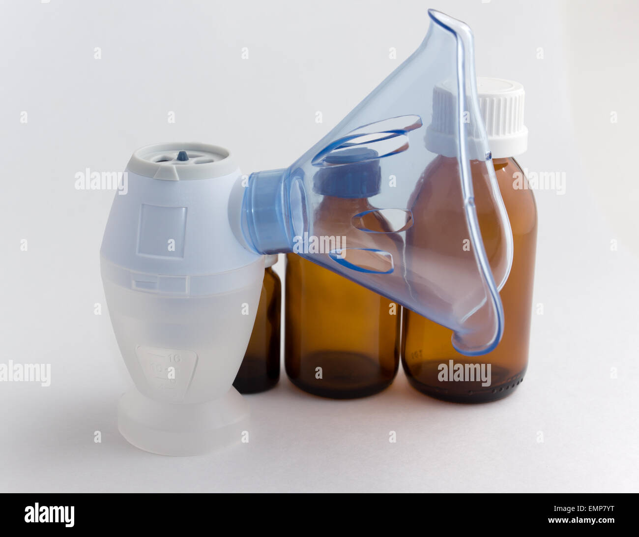 Inhalation mask on a white background behind which three jars with ...