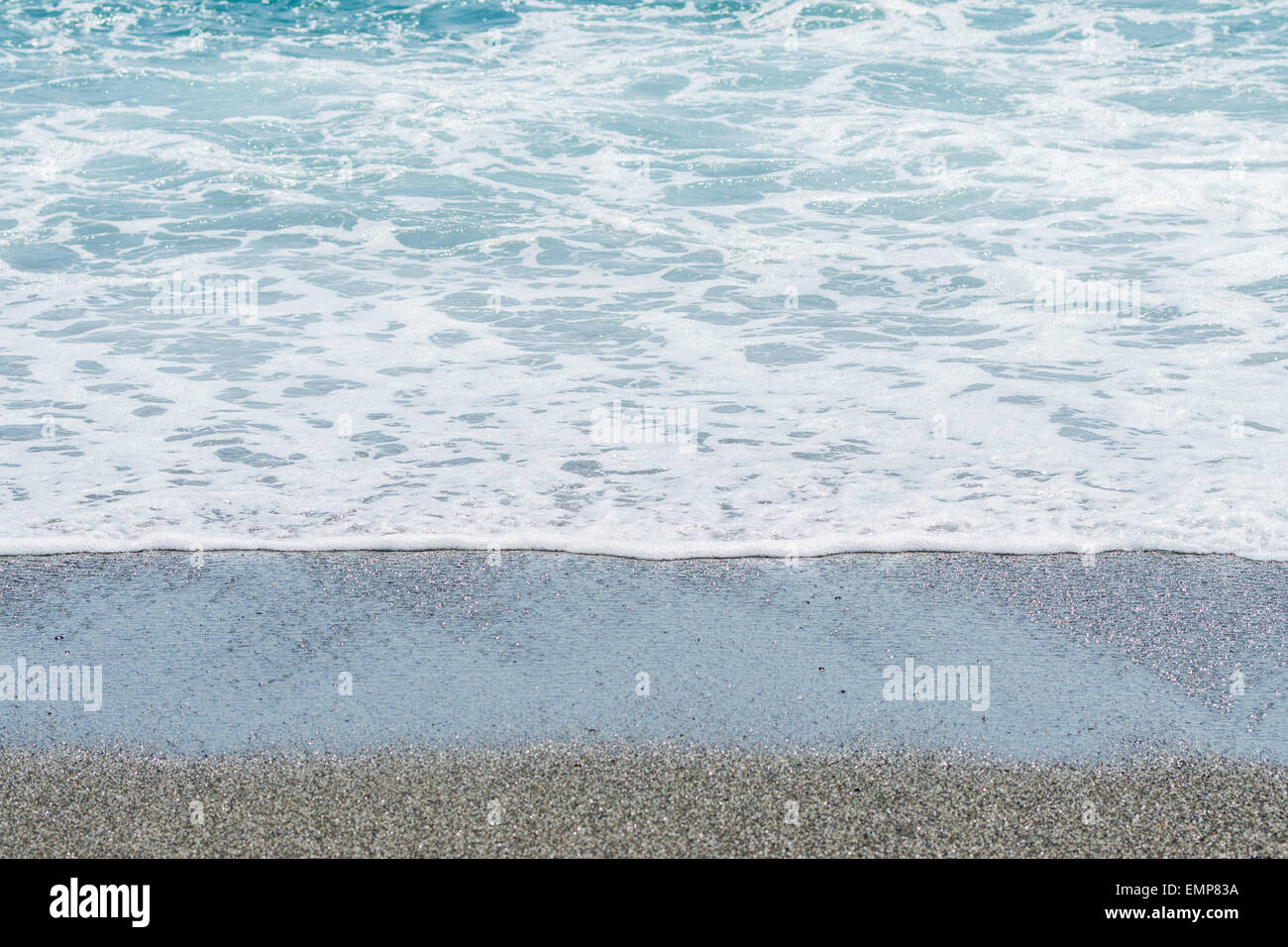 The tide coming in on a beach with wet sand Stock Photo - Alamy