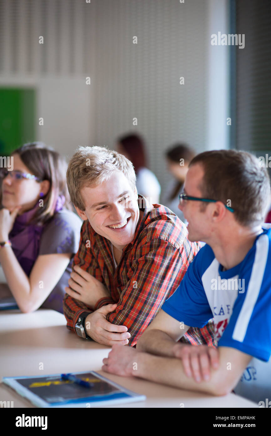 Handsome college student sitting in a classroom full of students during ...