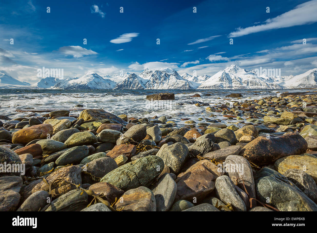 A sunny and windy Norwegian scenery with foreground rock boulders and ...