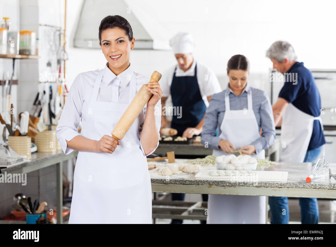 Female Chef Holding Rolling Pin While Colleagues Preparing Pasta Stock ...