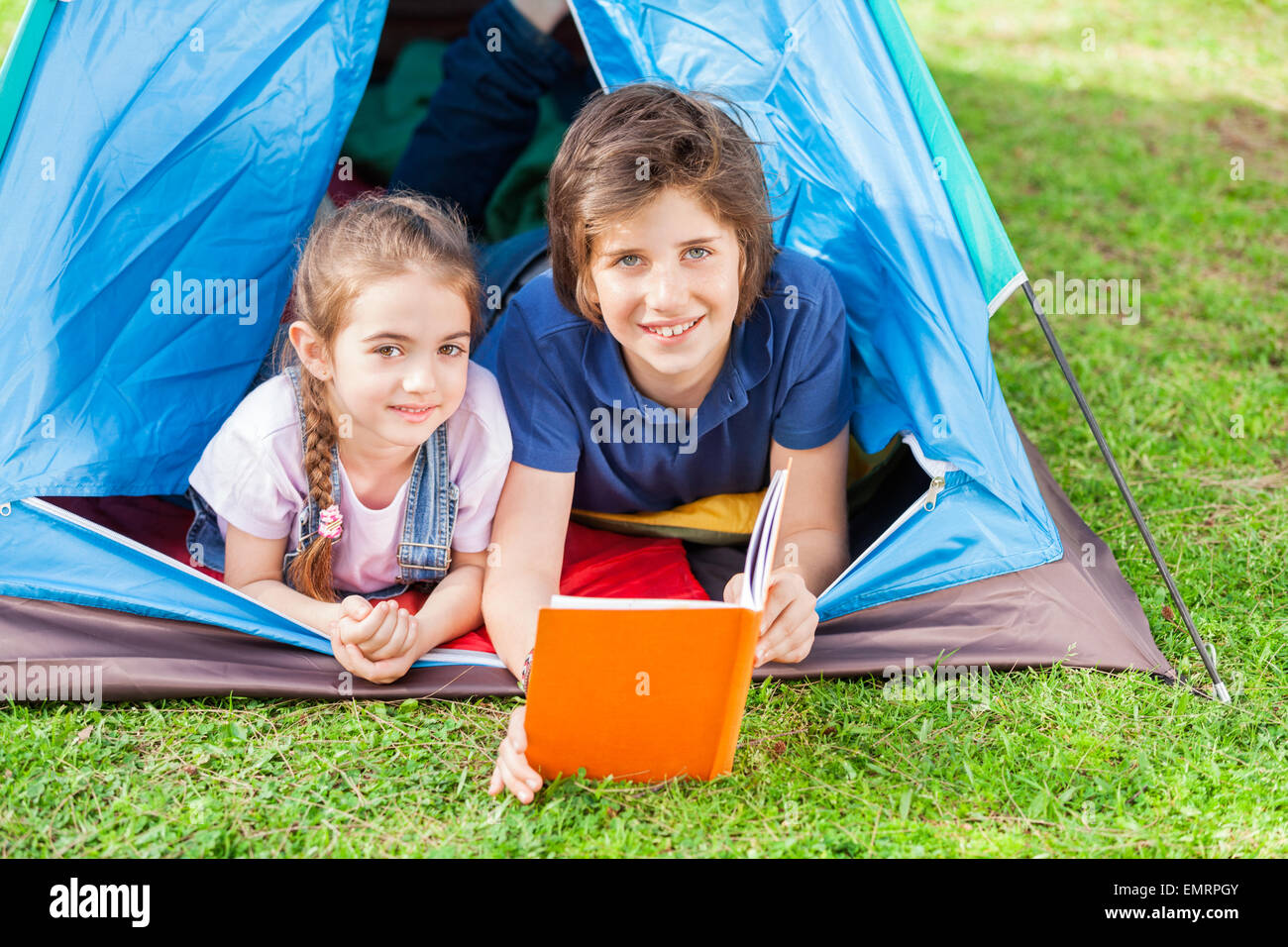 Siblings Reading Book In Tent Stock Photo - Alamy