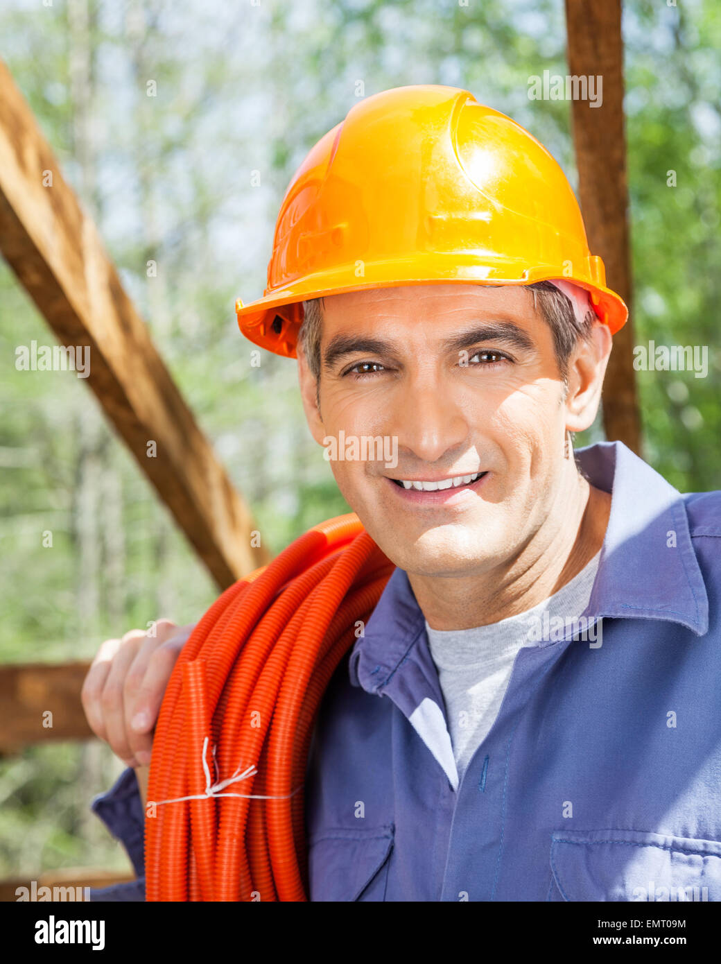 Smiling Construction Worker Carrying Rolled Pipe At Site Stock Photo ...