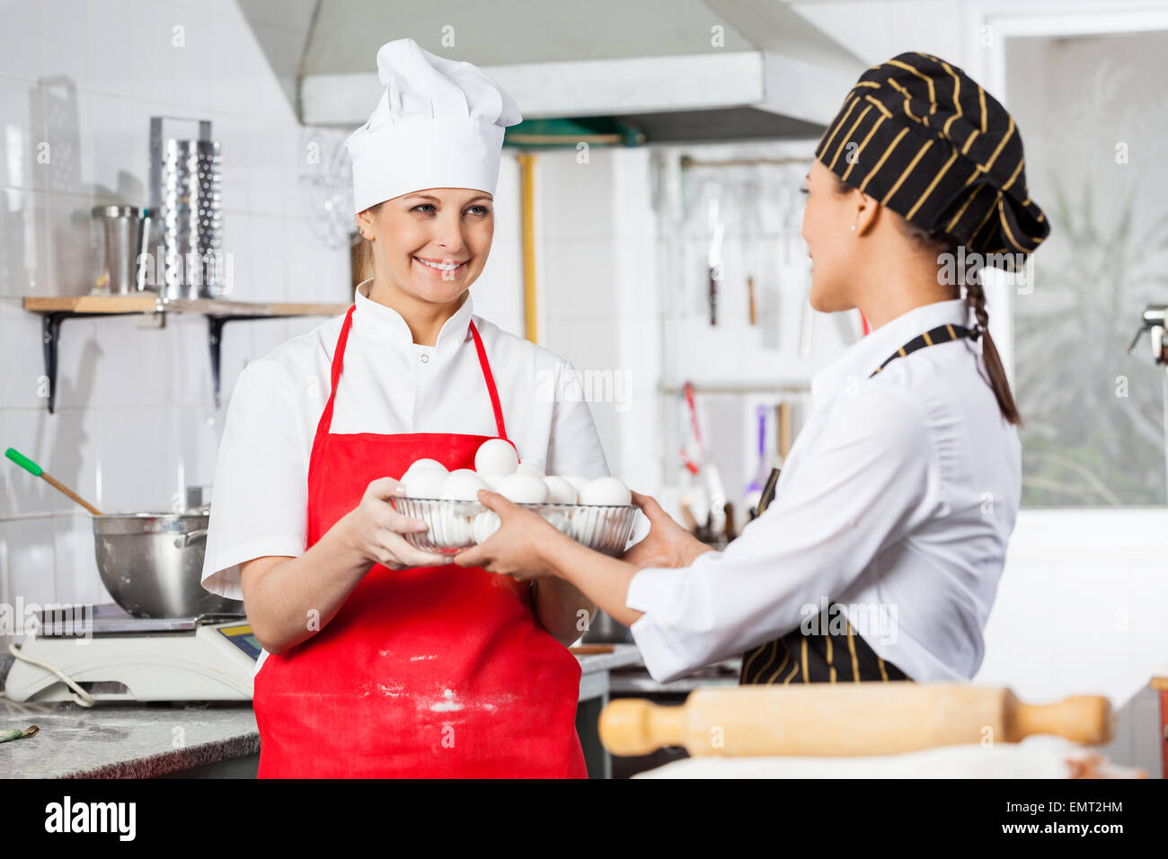 Happy Chef Giving Container Full Of Eggs To Colleague Stock Photo - Alamy