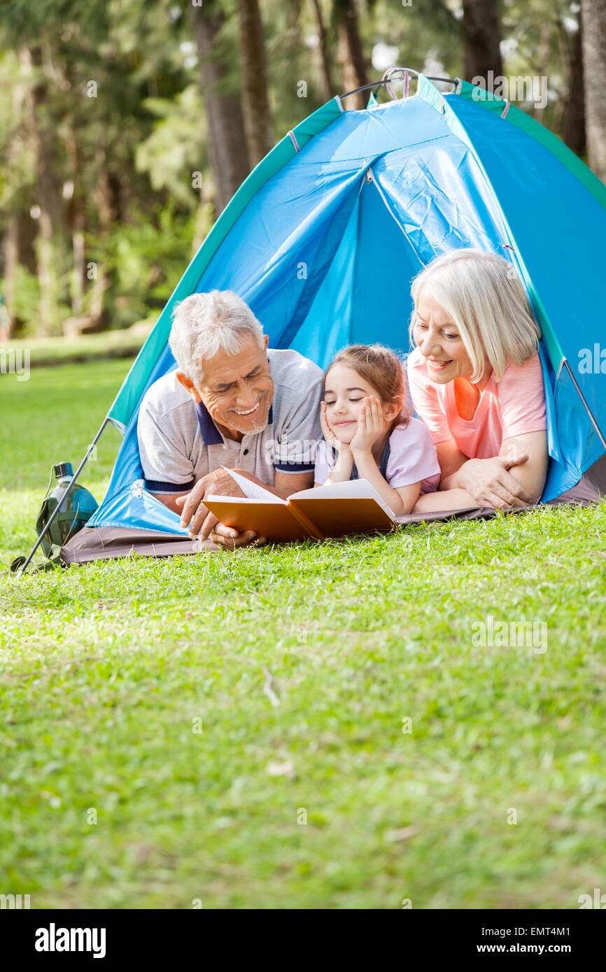 Grandparents Reading Book For Granddaughter At Campsite Stock Photo - Alamy