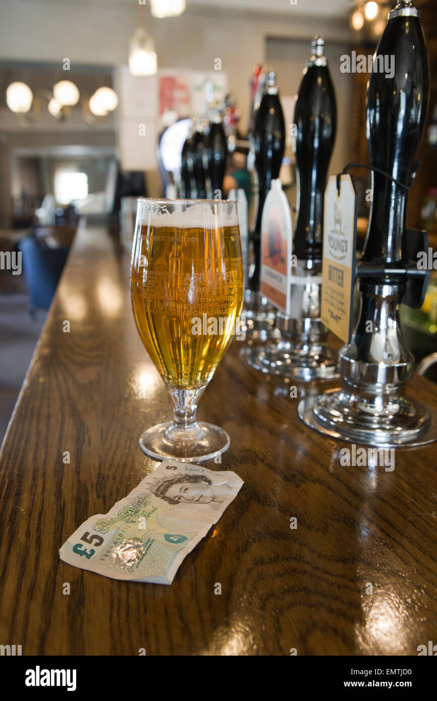 A pint of lager and a £5 note on a bar in a pub Stock Photo - Alamy