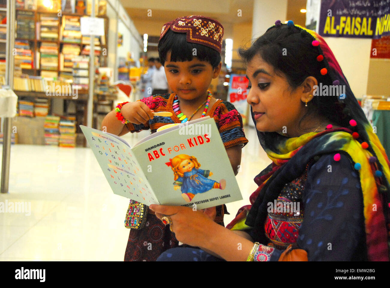 Islamabad, Pakistan. 23rd Apr, 2015. A woman and her child read a book ...