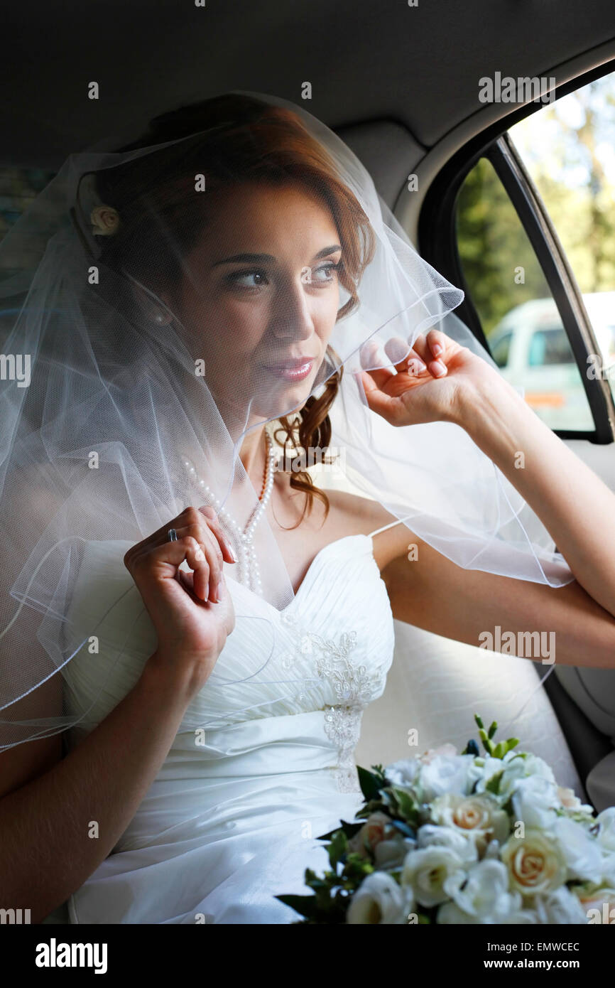 Beautiful bride with wedding bouquet in white car Stock Photo - Alamy