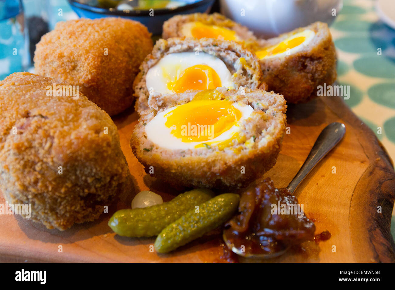 A soft boiled scotch egg cut open to show the egg gently pouring out of ...