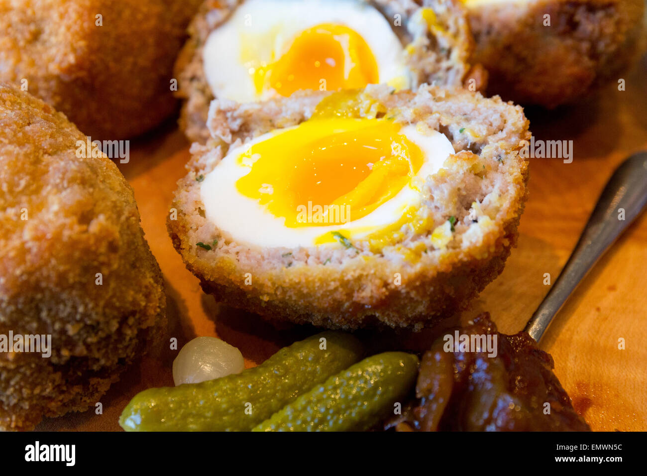A soft boiled scotch egg cut open to show the egg gently pouring out of ...
