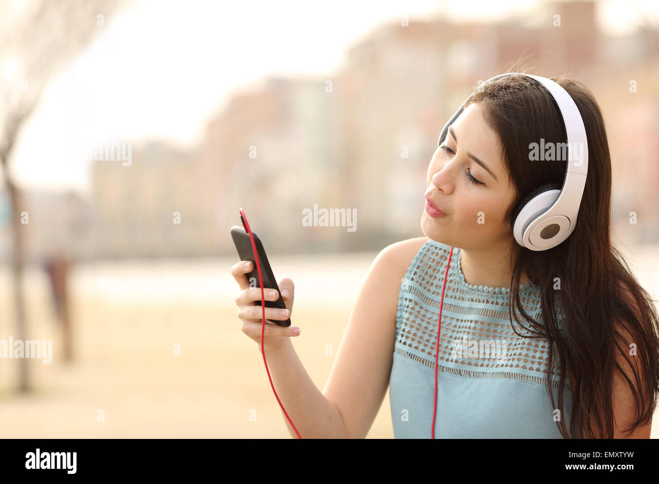 Funny teen girl singing and listening music from a smart phone with ...