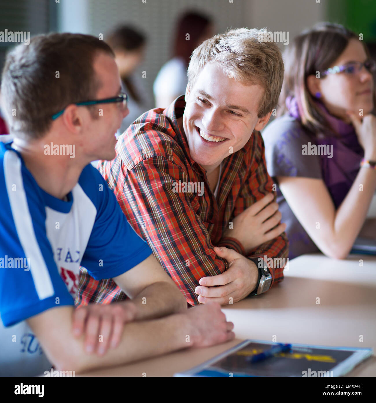 Handsome college student sitting in a classroom full of students during ...