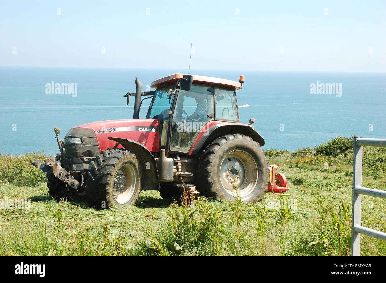 A red tractor in a field by the coast Stock Photo - Alamy