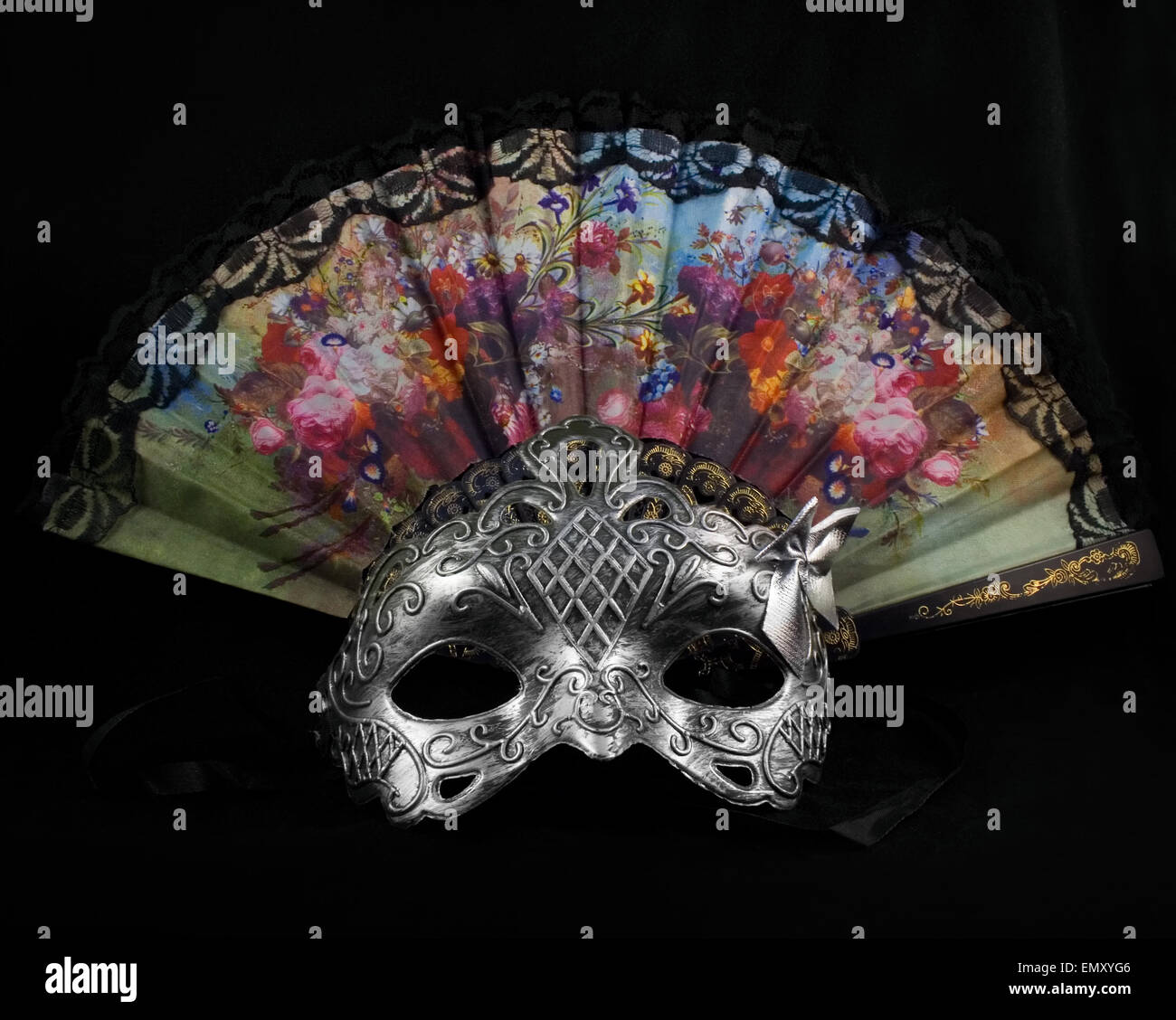 Mask with fan.Silver carnival mask laying with folding fan on black ...