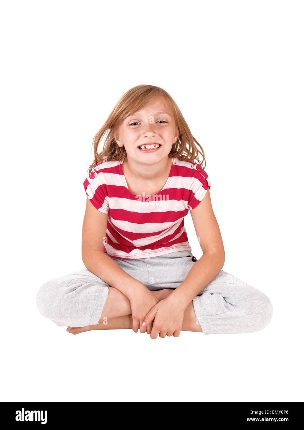 A very happy young girl sitting smiling on the floor in the studio ...