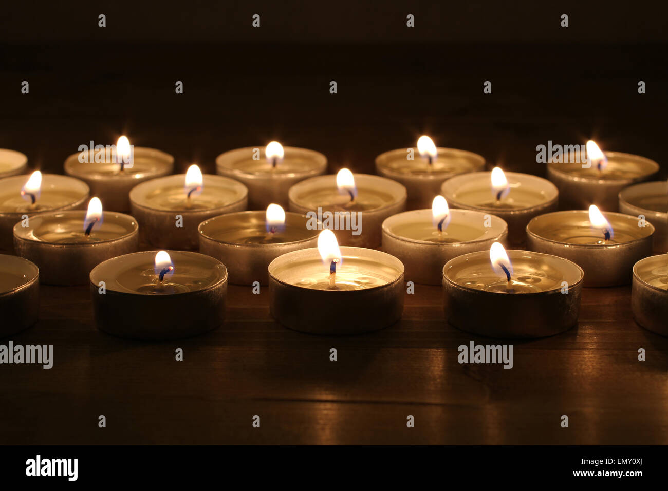 Blazing candles arranged in alignments on brown toned wooden table ...