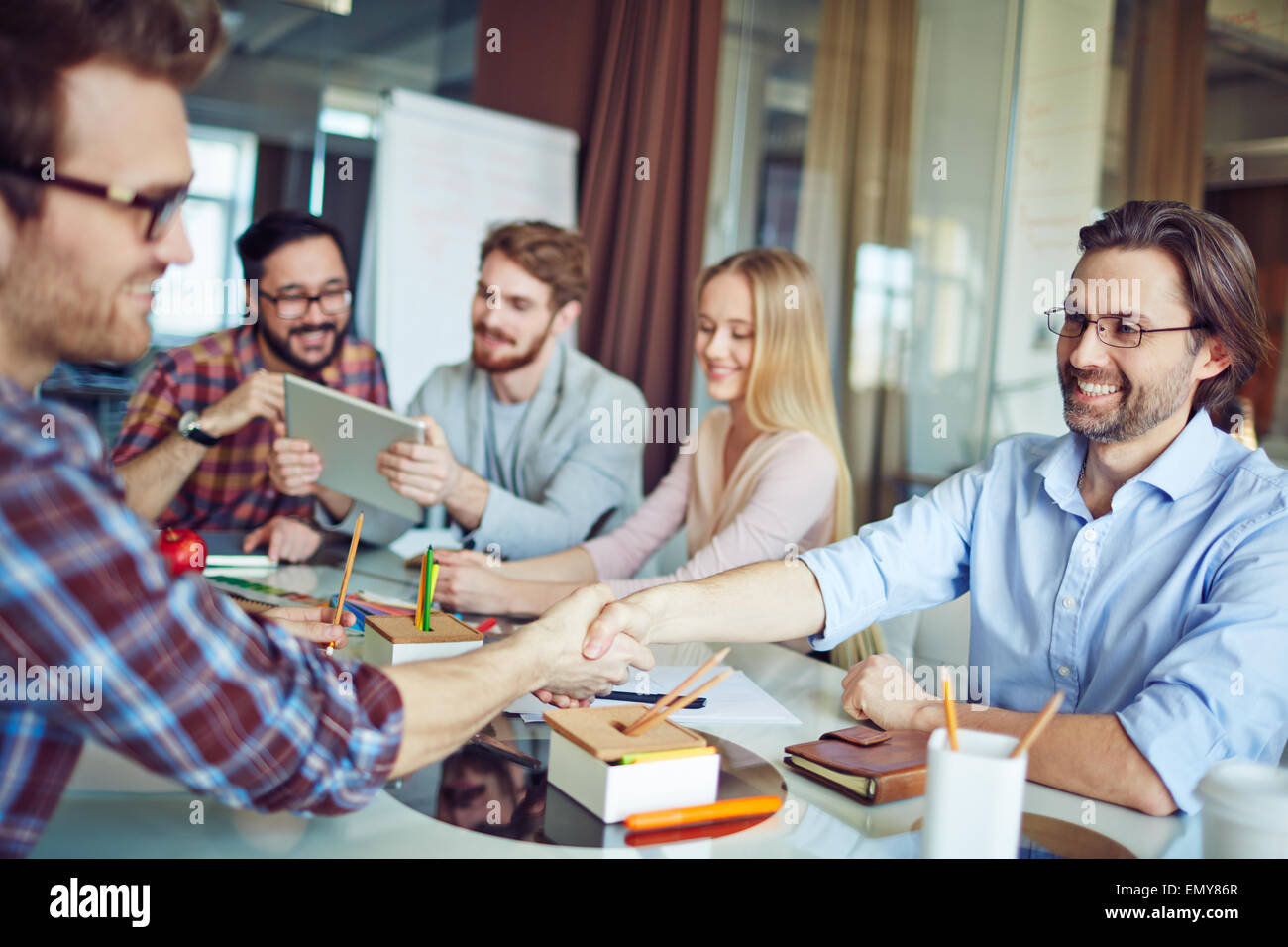 Businessmen handshaking on background of working team Stock Photo - Alamy