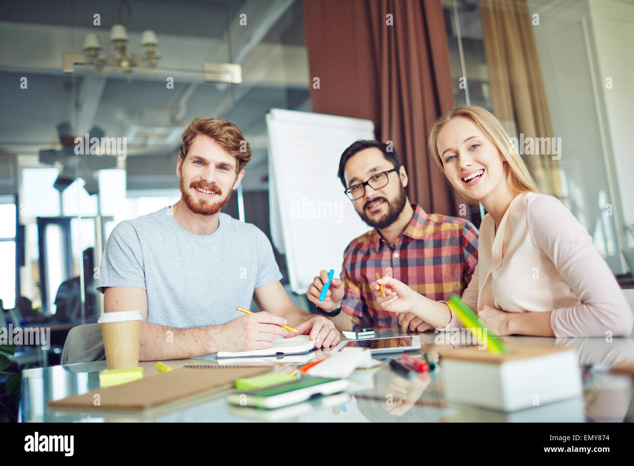 Group of three cheerful business partners looking at camera Stock Photo ...
