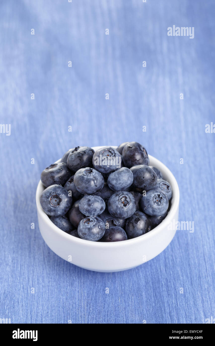 heap of fresh washed blueberries in white bowl on blue wood table Stock ...