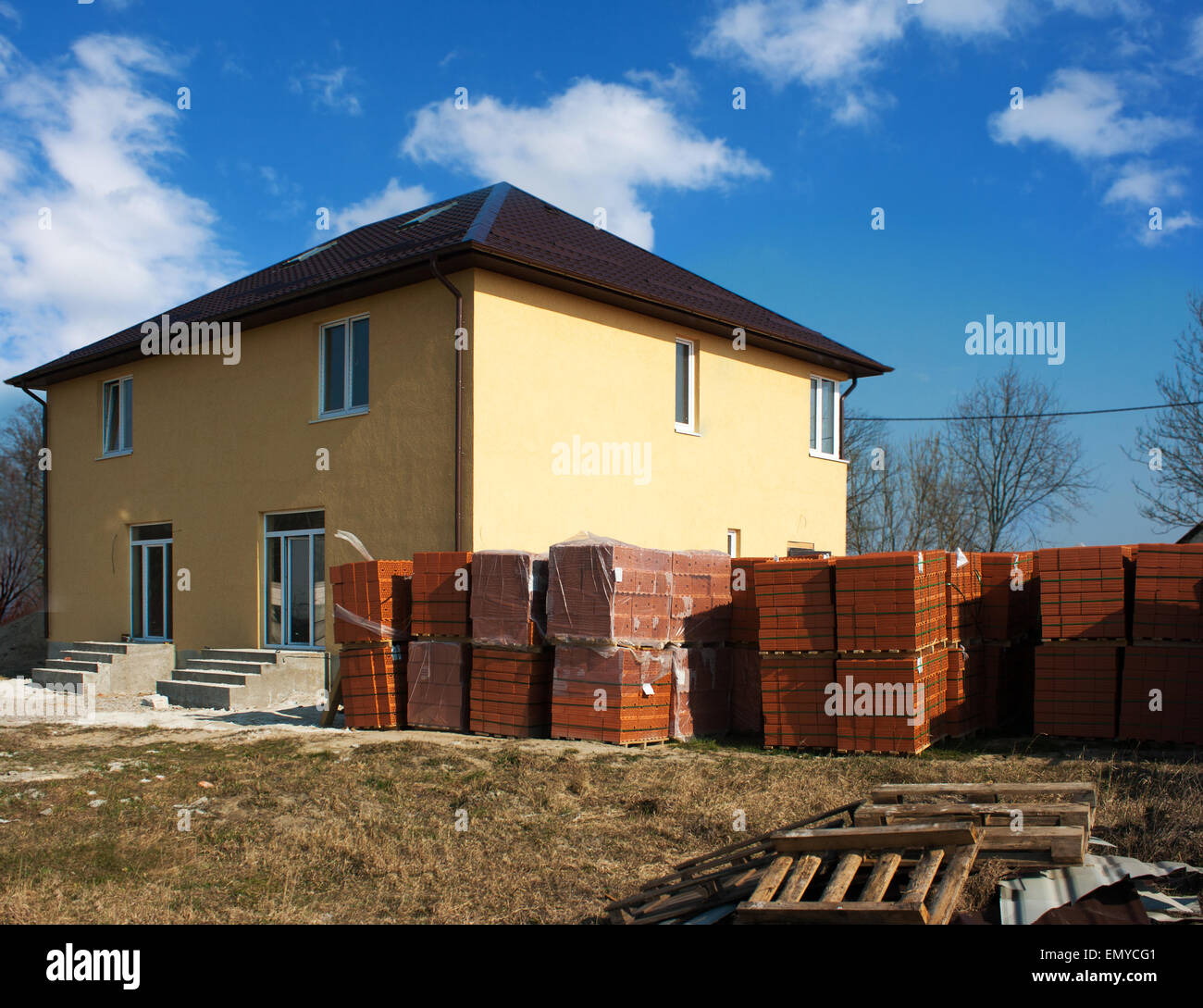new yellow house with stacks of red bricks for the construction on ...