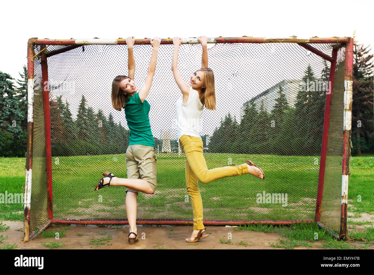 Young women having fun hanging by vintage soccer goal. Attractiv Stock ...