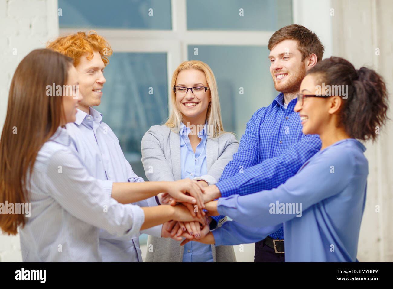 team with hands on top of each other in office Stock Photo - Alamy