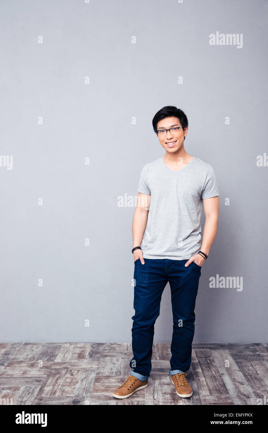 Full length portrait of a smiling asian man standing in studio and ...