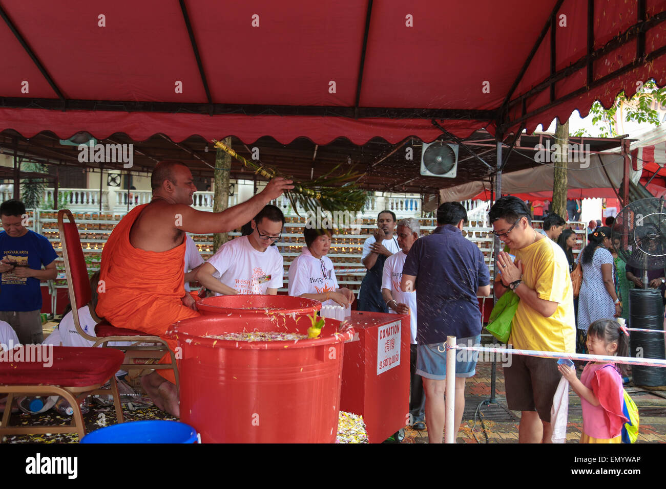 Family are getting holy water blessing from a priest at Buddhist Maha ...