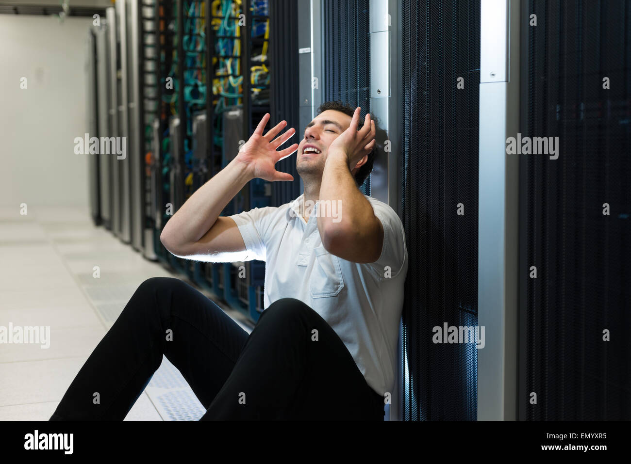 Business man sitting in a data center looking frustrated with the ...