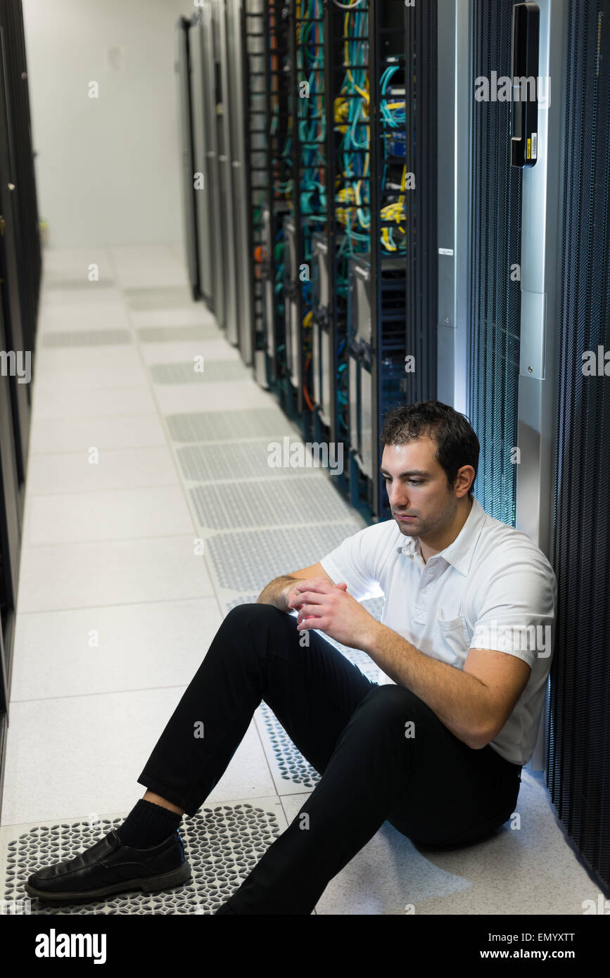 Business man sitting in a data center looking frustrated with the ...