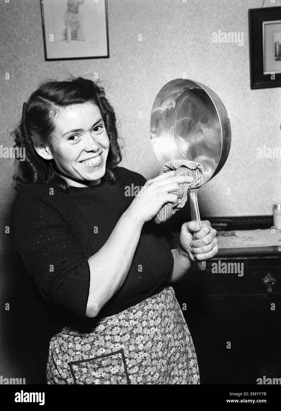 Woman seen in the kitchen drying a frying pan. Circa February 1952 ...