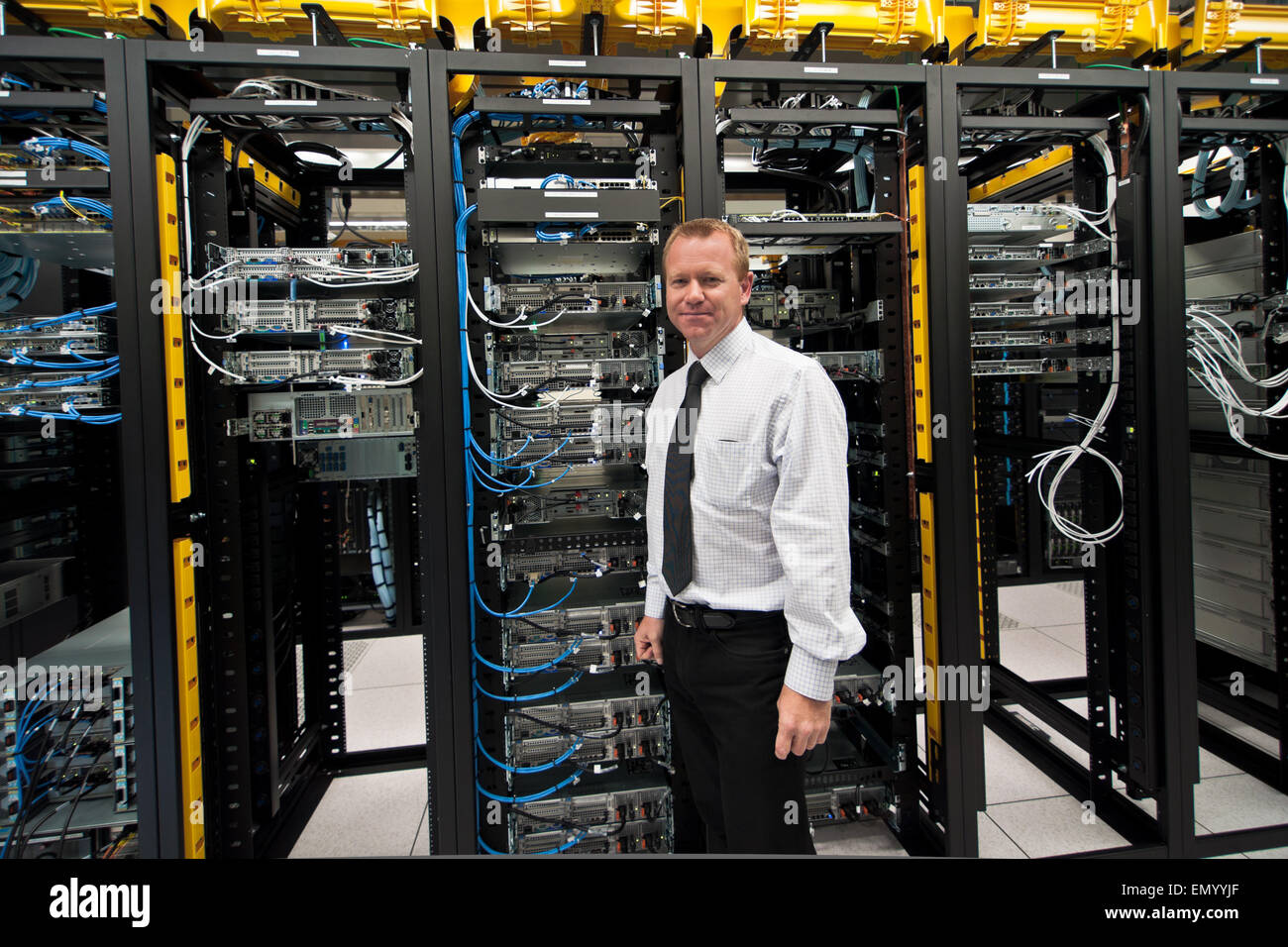 A happy datacenter manager posing in front of the datacenter equipment ...