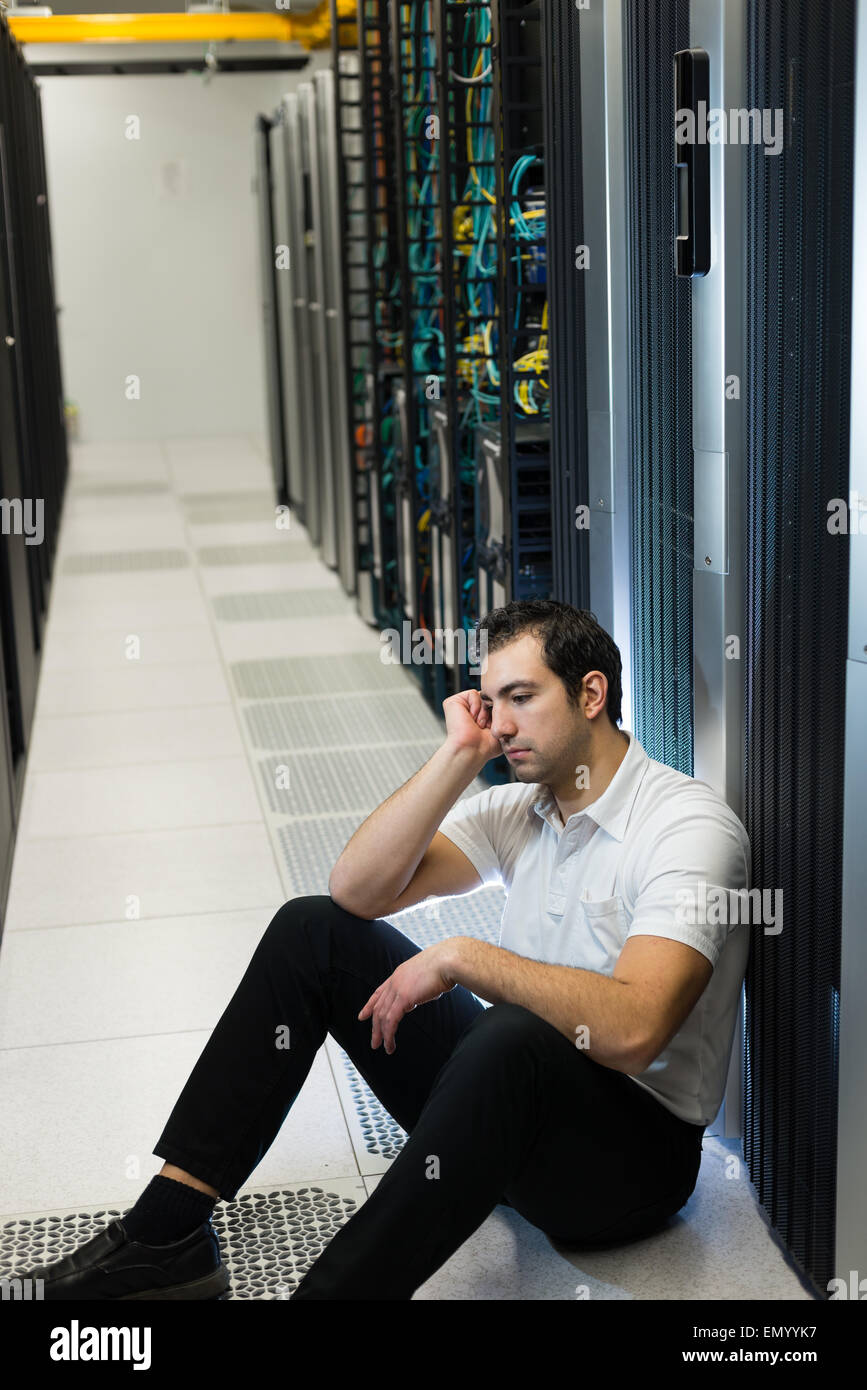 Business man sitting in a data center looking frustrated with the ...