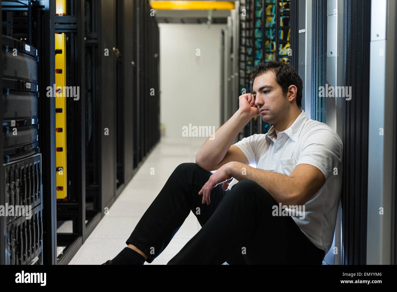 Business man sitting in a data center looking frustrated with the ...