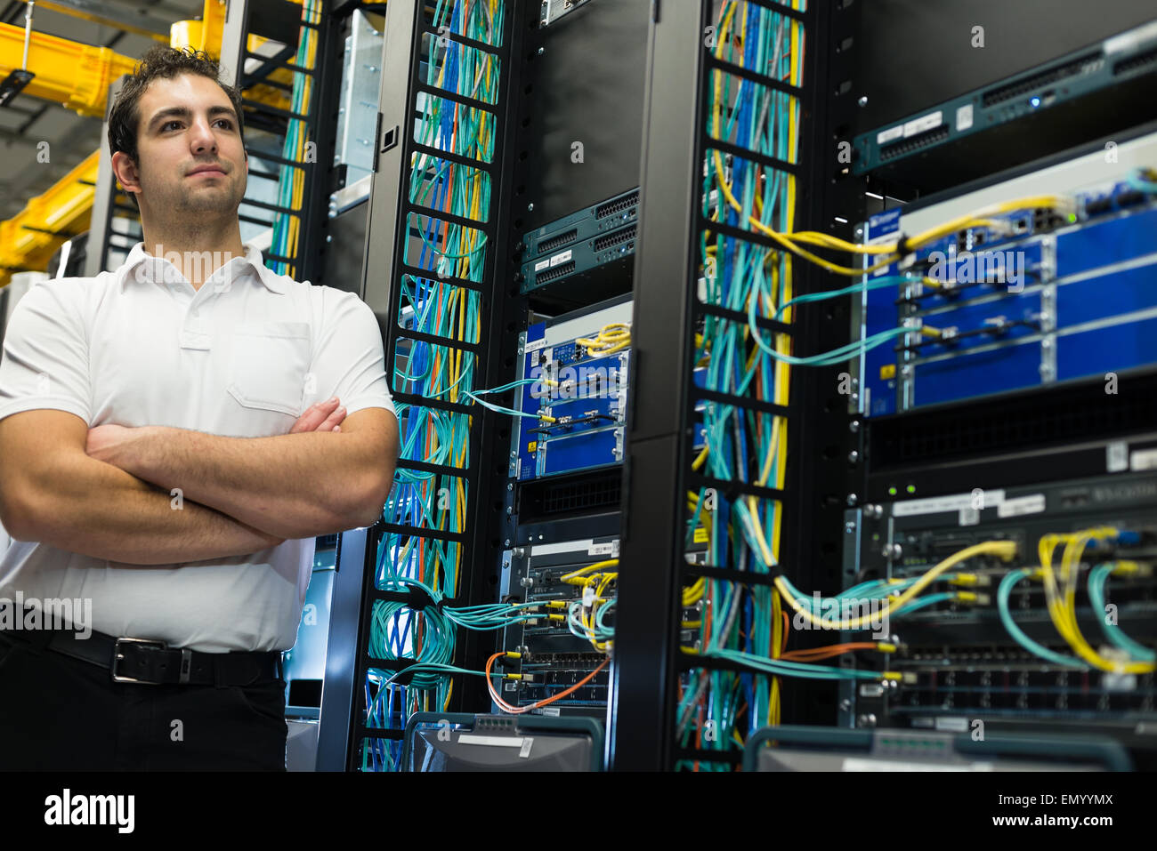 A happy datacenter manager posing in front of the datacenter equipment ...