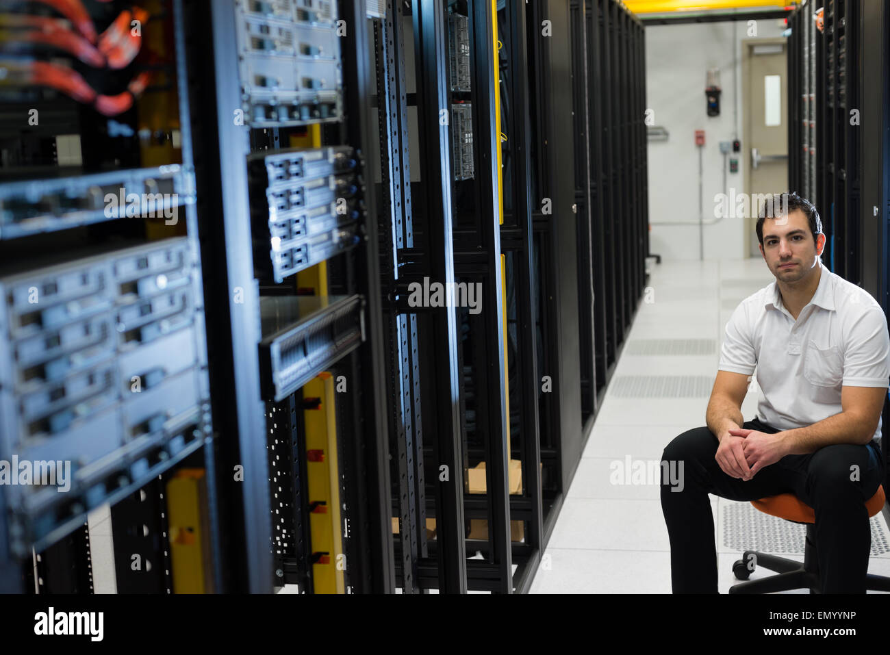 A happy datacenter manager posing in front of the datacenter equipment ...