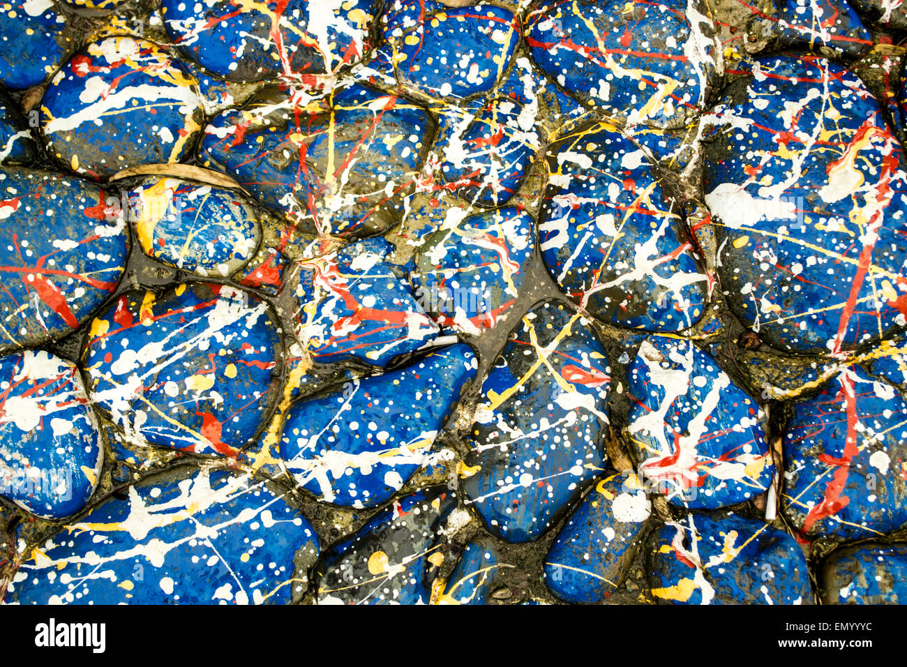 Stones covered in paint drops and drips creating a distinctive splatter ...