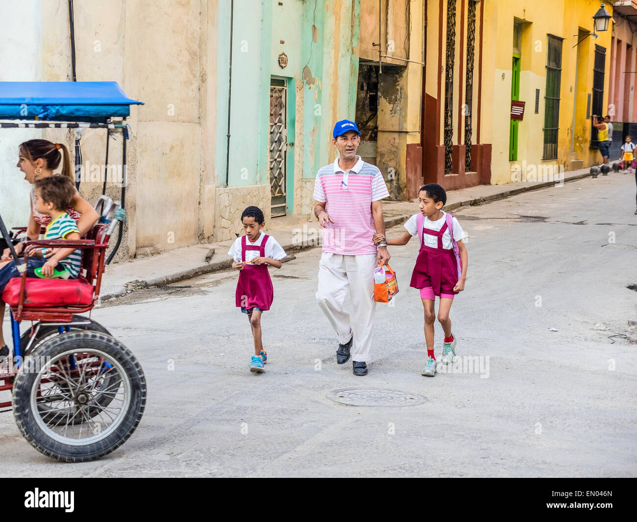 A Hispanic Cuban father walks his two young daughters, who are dressed ...