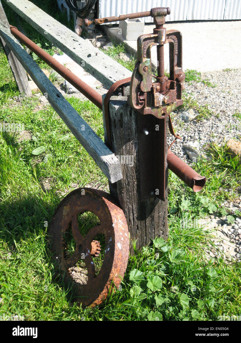 The rusted handle of an old water pump and wheel lying in the sun on a ...