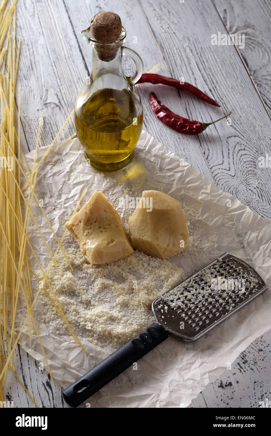 Grated parmesan cheese, bottle of olive oil and metal grater on wooden ...