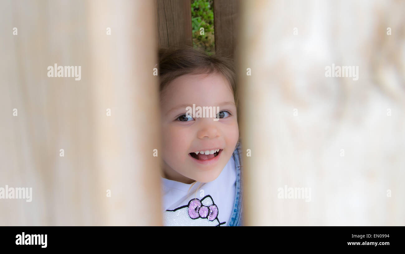 child laughs hidden behind a wooden fence Stock Photo - Alamy