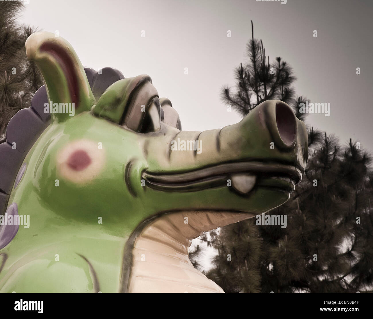 A happy dragon on a children's ride looks towards camera under a dark ...