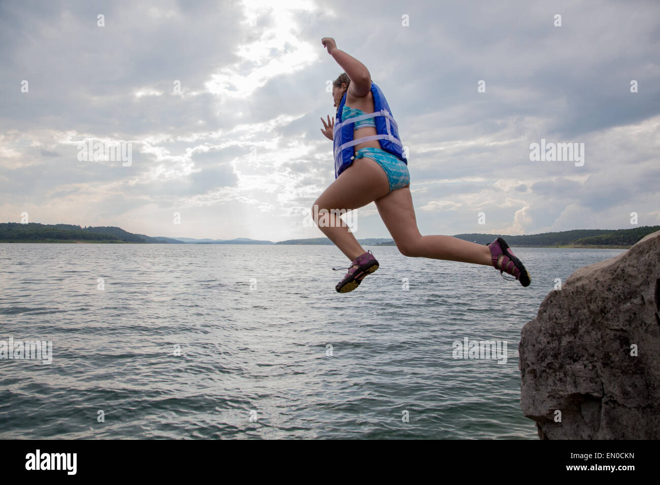 A group of friends jump from cliffs into the lake Stock Photo - Alamy