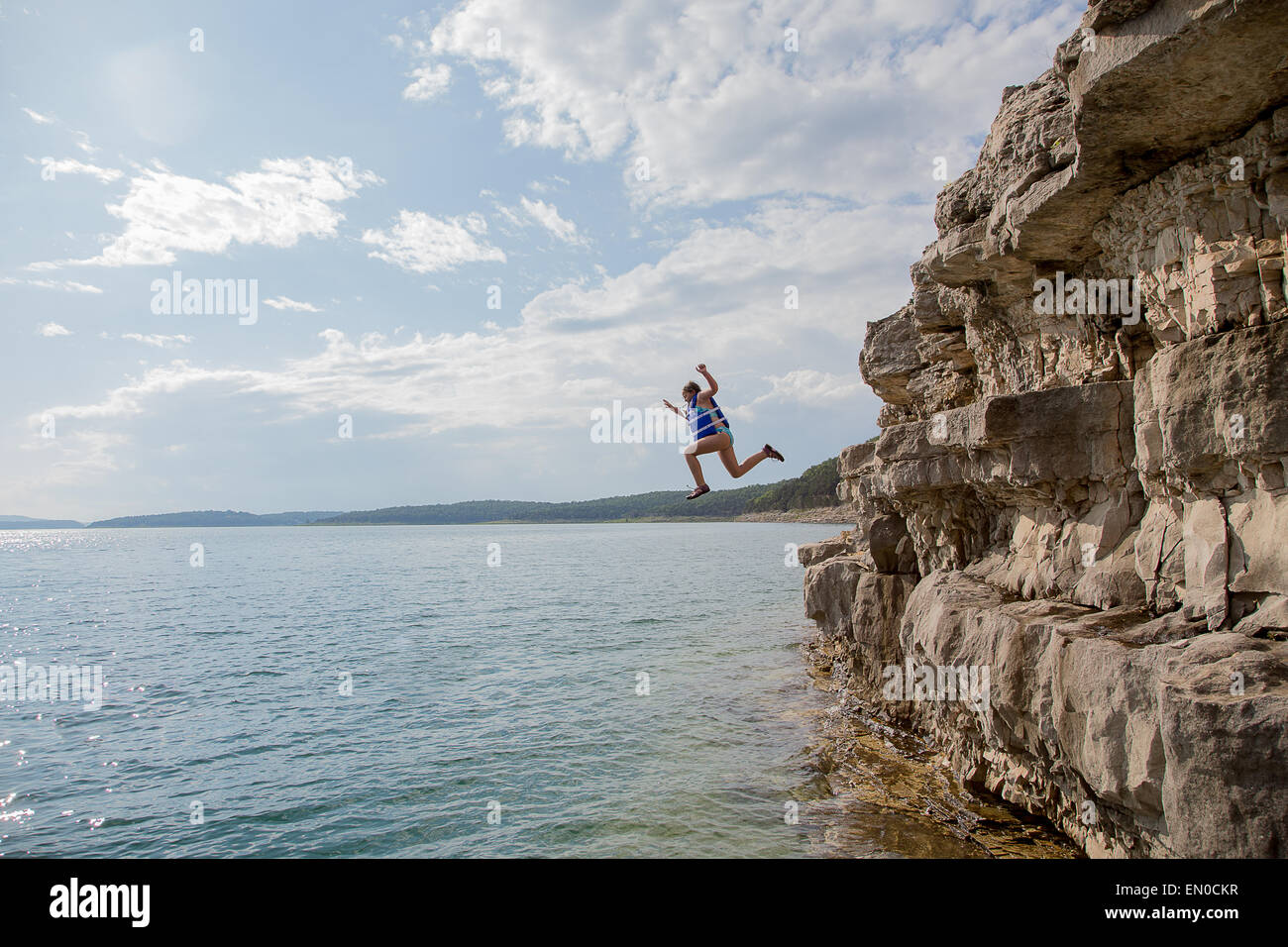 A group of friends jump from cliffs into the lake Stock Photo - Alamy
